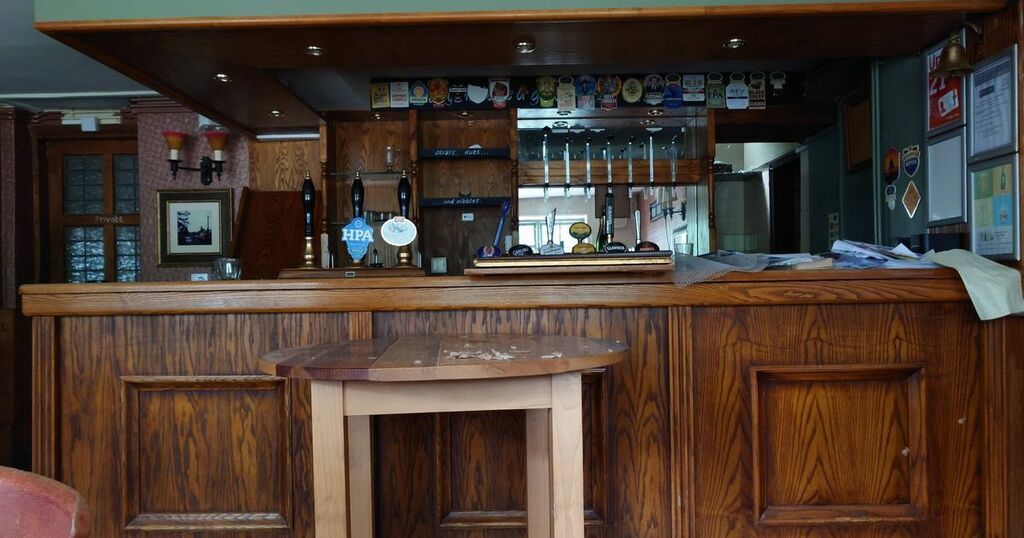 Inside abandoned pub with pint glasses half full that…