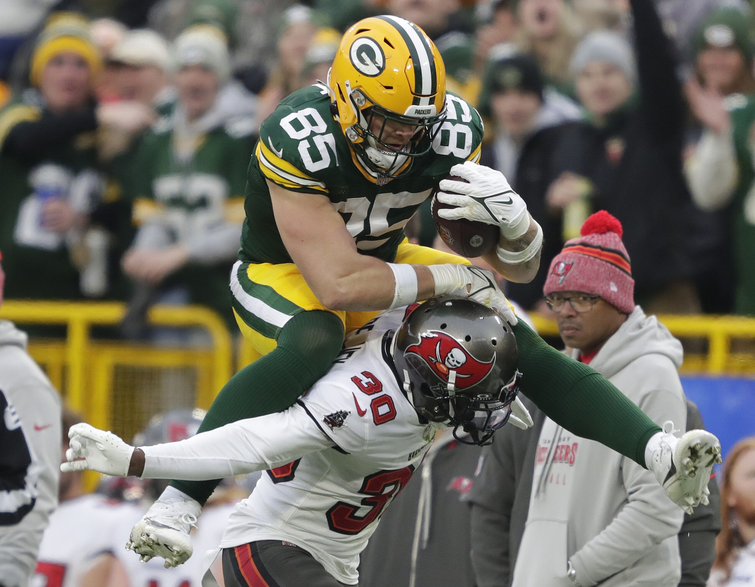 Packers TE Tucker Kraft hurdles a defender and gets…