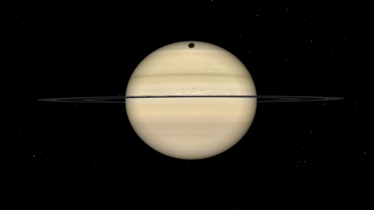 Titan's shadow crosses Saturn as the planet offers up…